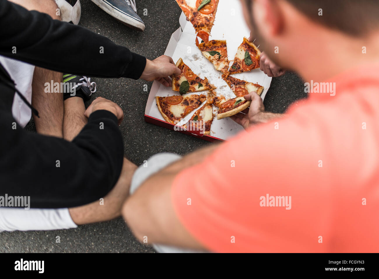 Young men eating pizza Stock Photo - Alamy