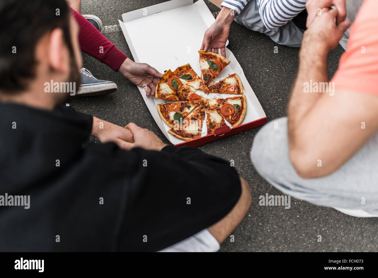 Young men eating pizza Stock Photo - Alamy