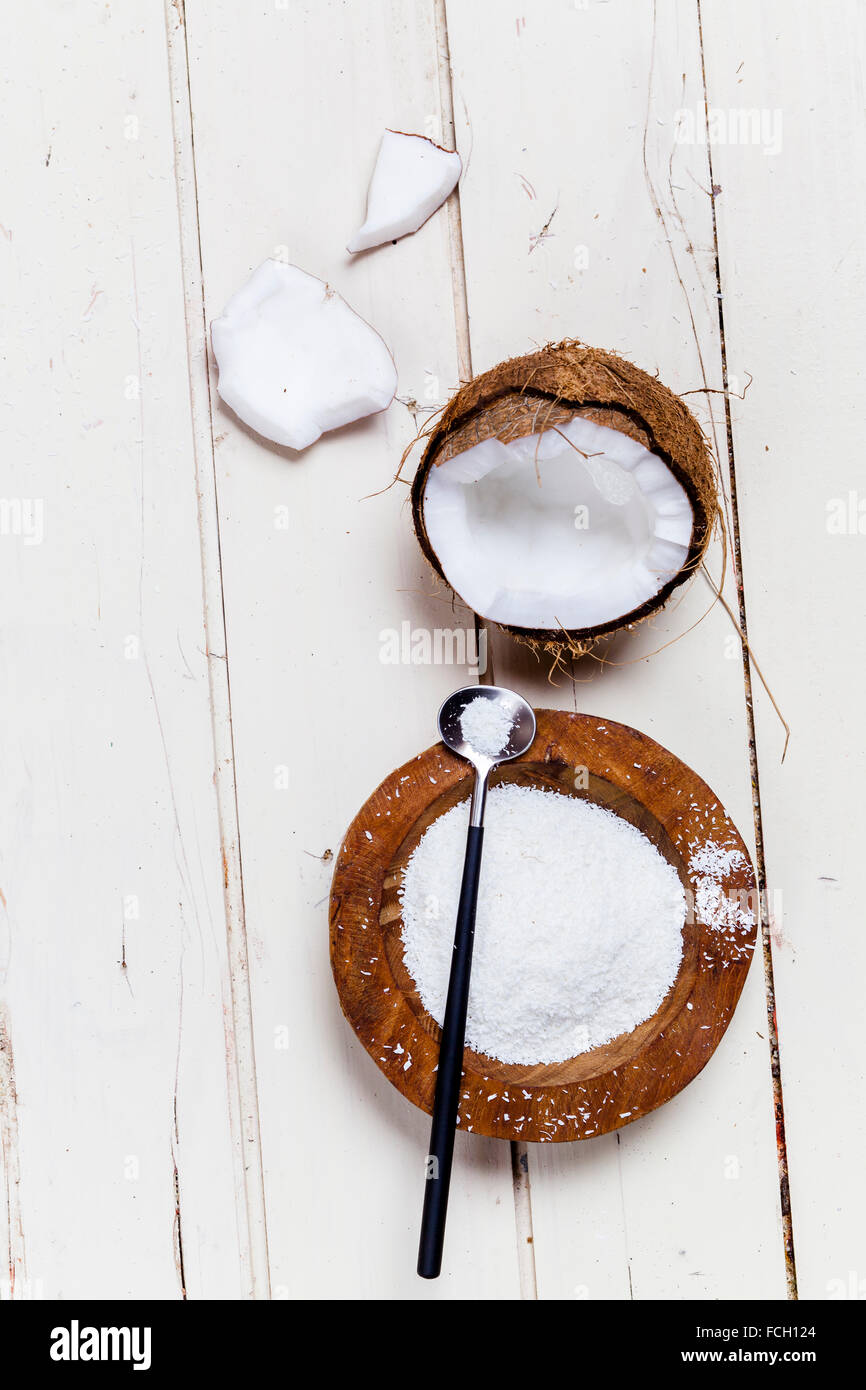 Opened coconut and wooden bowl of coconut flakes on white wood Stock ...