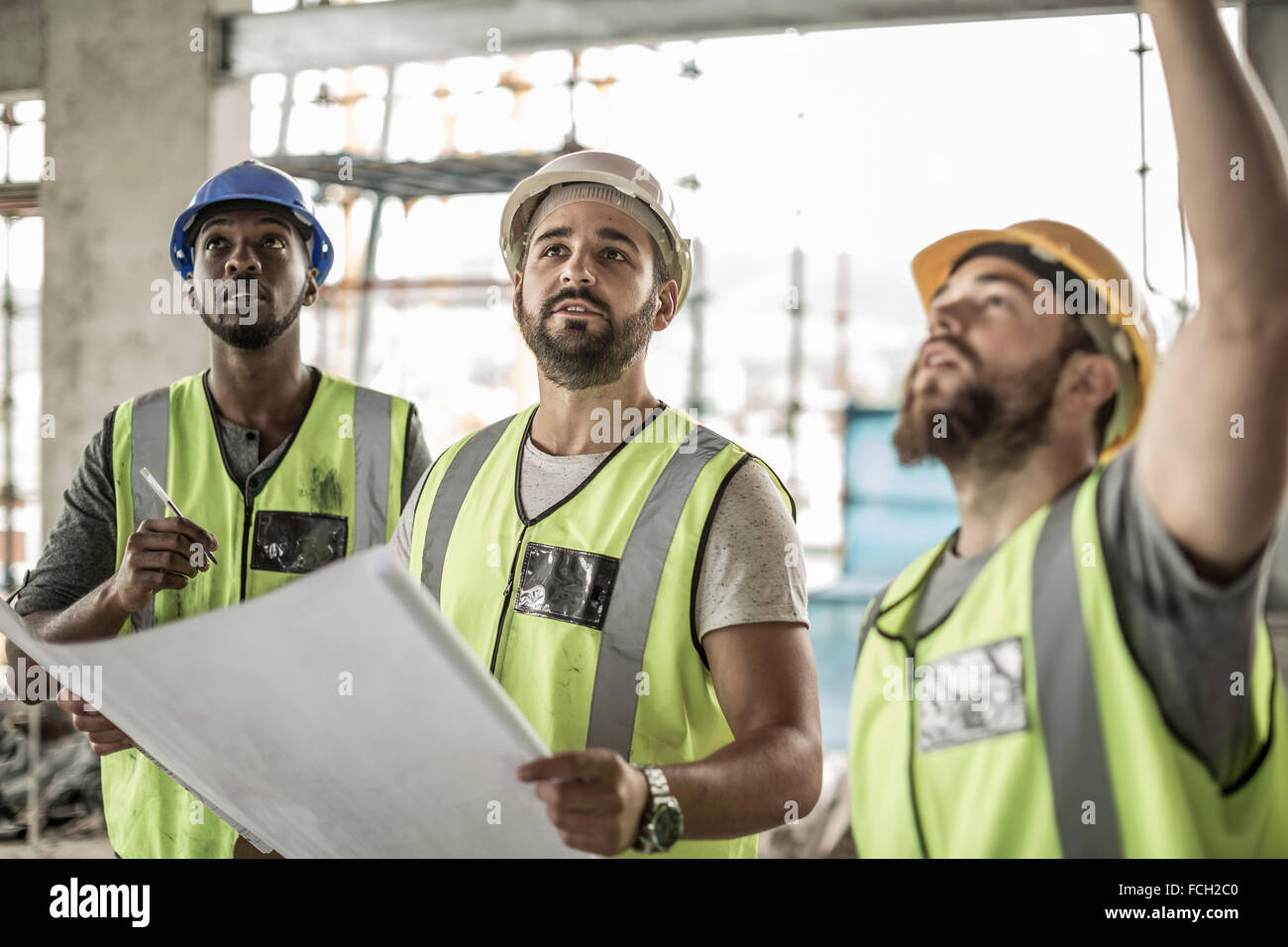 Construction workers discussing building plan in construction site ...