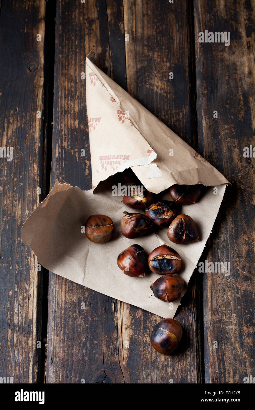 Paper bag roasted chestnuts on dark wood Stock Photo - Alamy