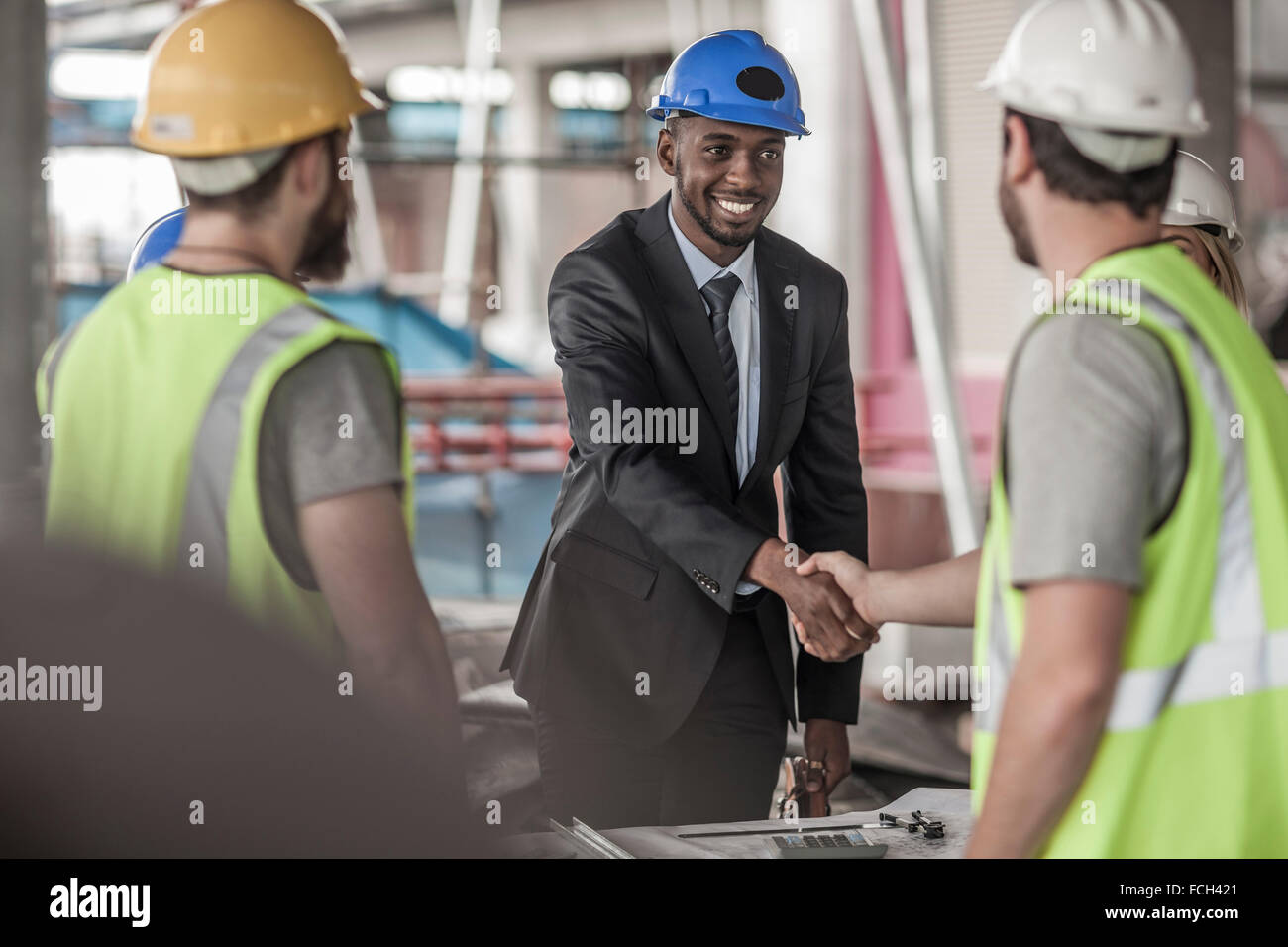 Construction worker and executive shaking hands in construction site ...