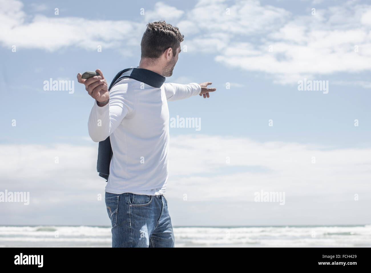 Man standing on the beach throwing pebble into the sea Stock Photo - Alamy