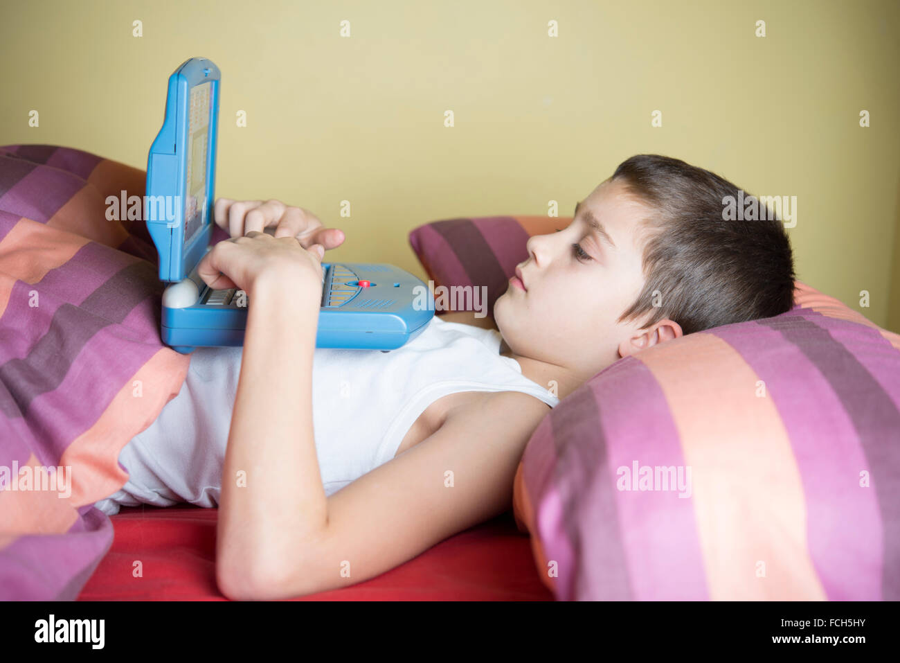 Boy playing with computer in bed Stock Photo - Alamy