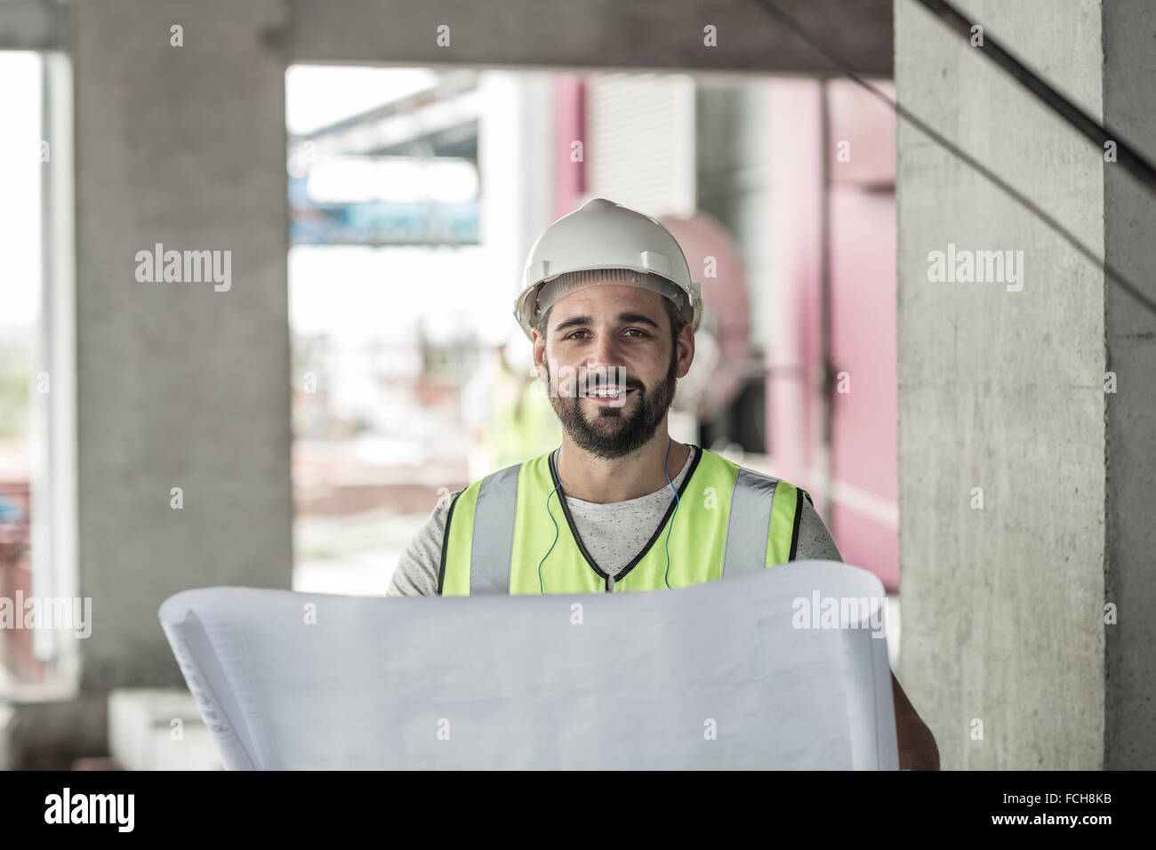 Portrait of smiling construction worker construction plan in ...