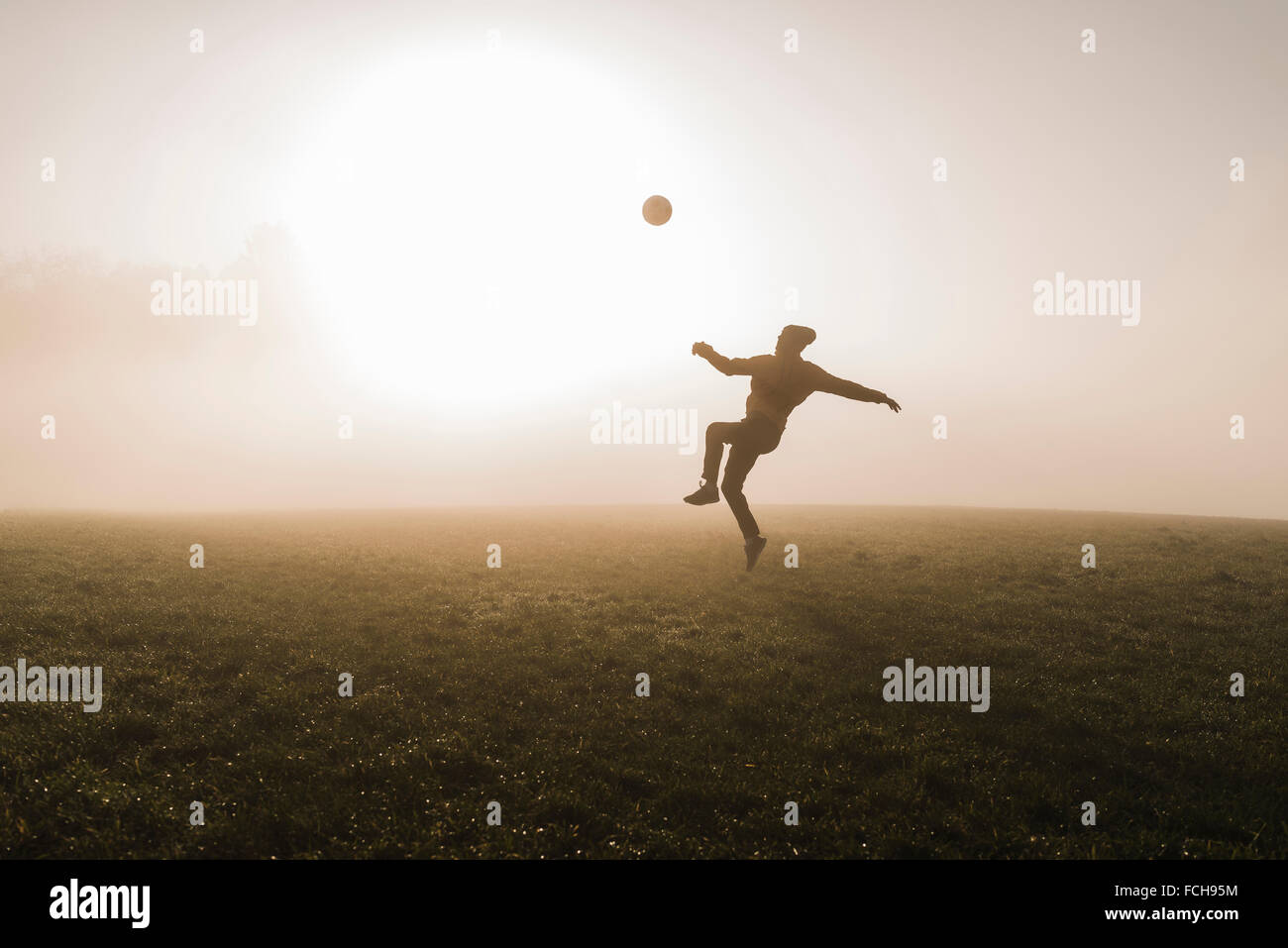 Young man playing soccer on meadow in the evening Stock Photo - Alamy