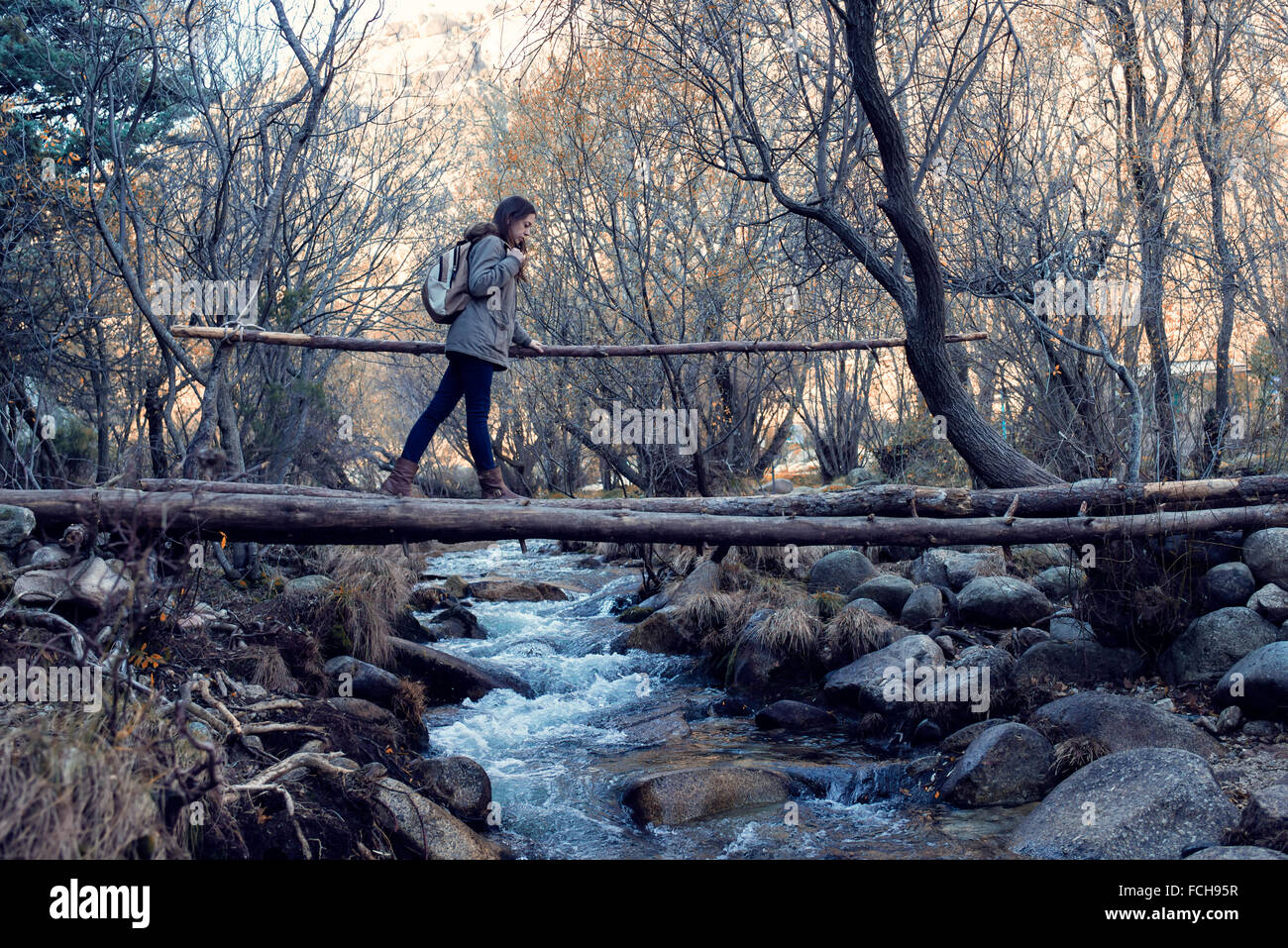 Young woman crossing a bridge made of tree trunks Stock Photo - Alamy