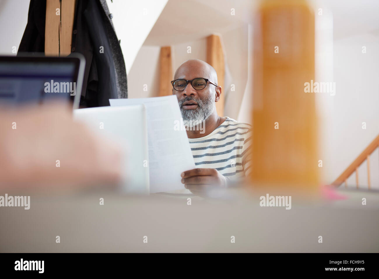 Portrait of man sitting at his desk reading papers Stock Photo - Alamy
