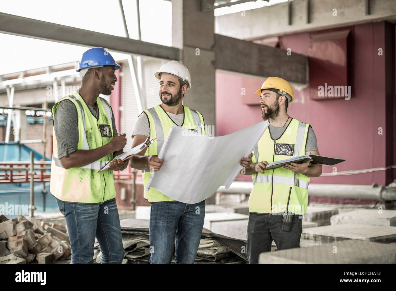 Construction workers discussing building plan in construction site ...