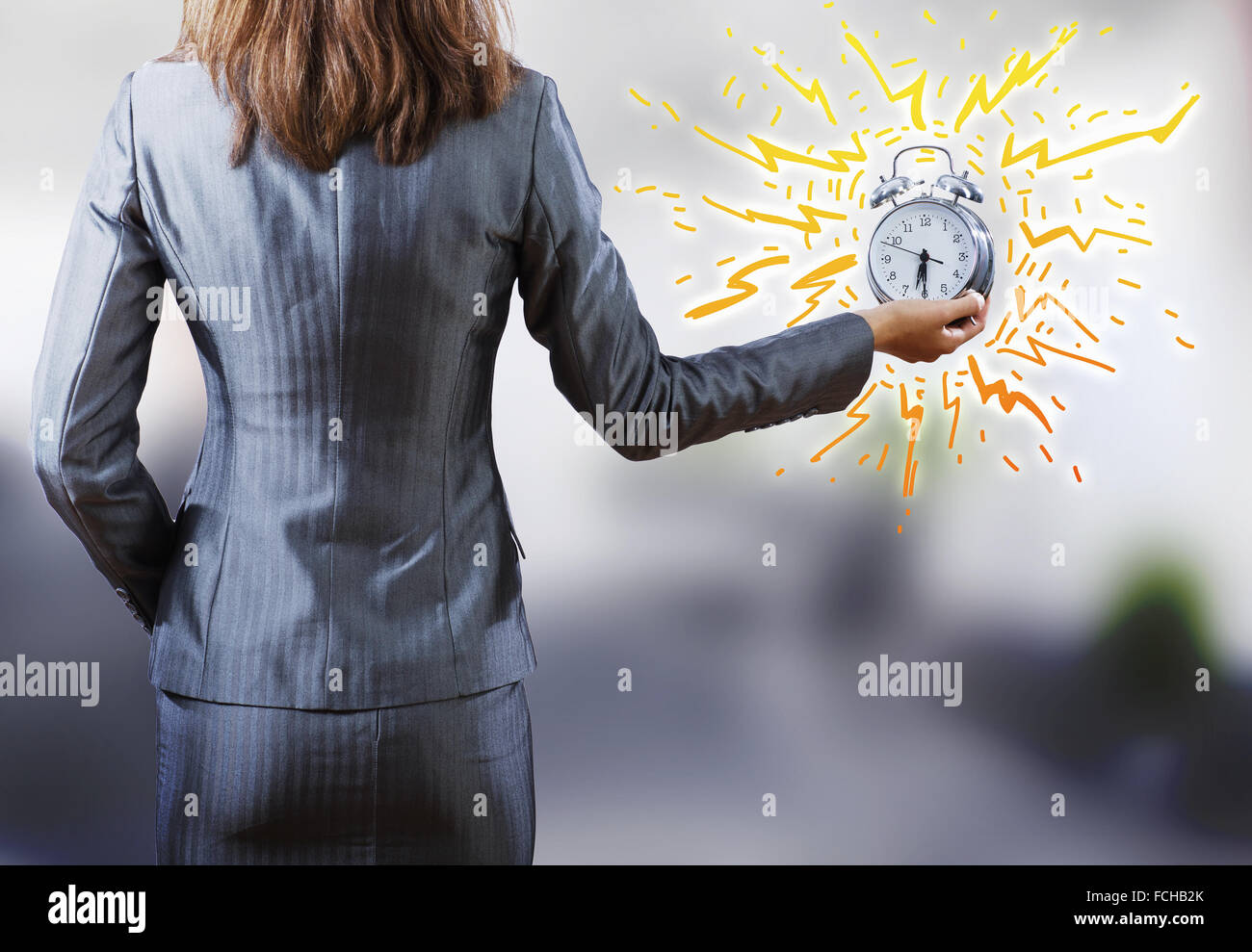 Rear view of businesswoman holding old alarm clock Stock Photo - Alamy