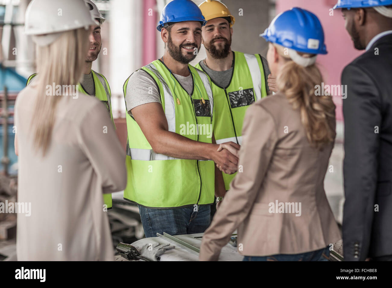 Construction worker and executive shaking hands in construction site ...