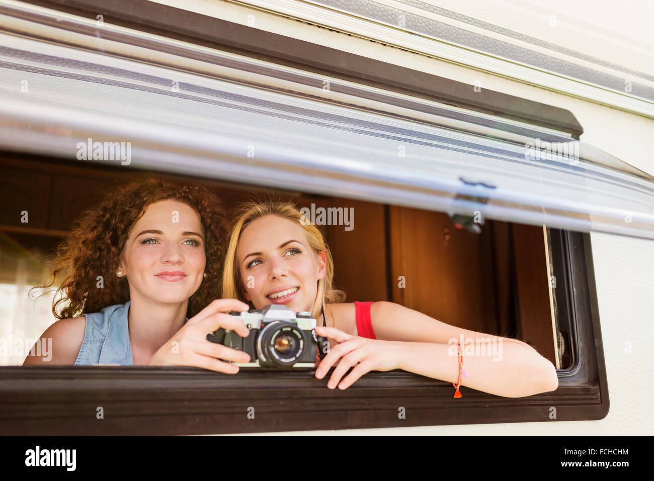 Two female friends camera looking through window of caravan watching ...