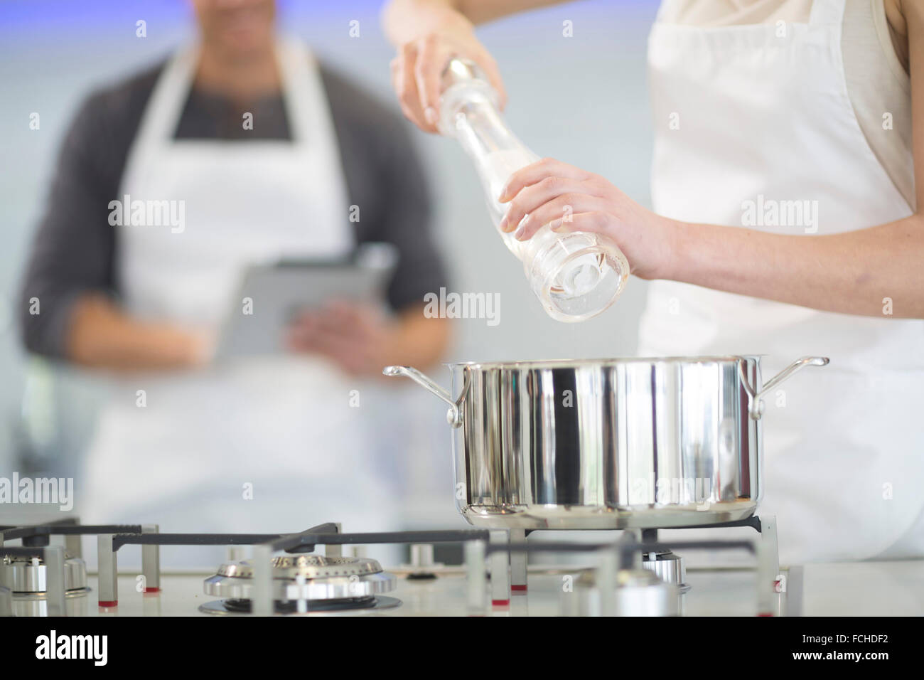 Woman salting dish in cooking pot Stock Photo - Alamy