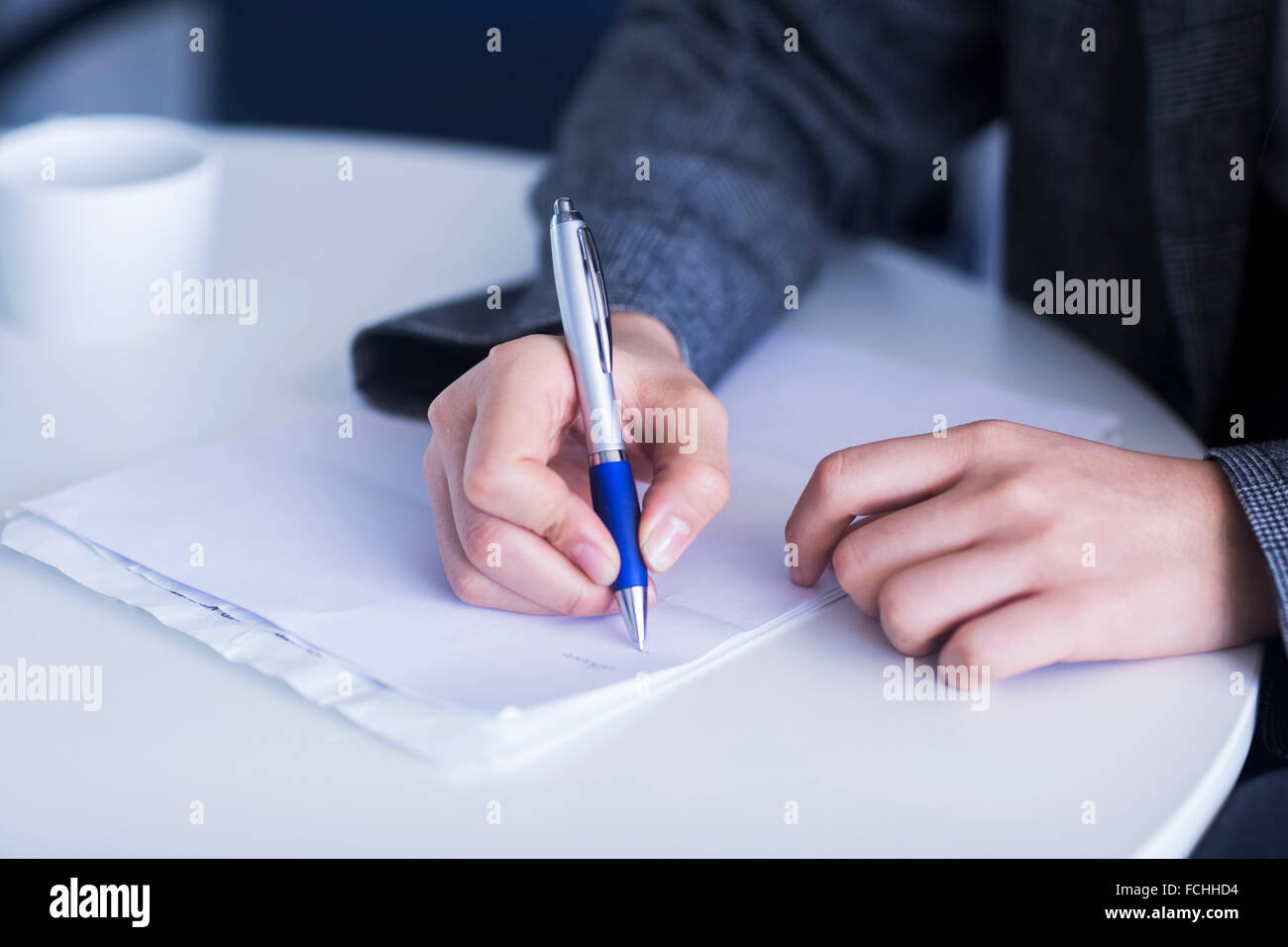 Woman in office writing on piece of paper Stock Photo - Alamy