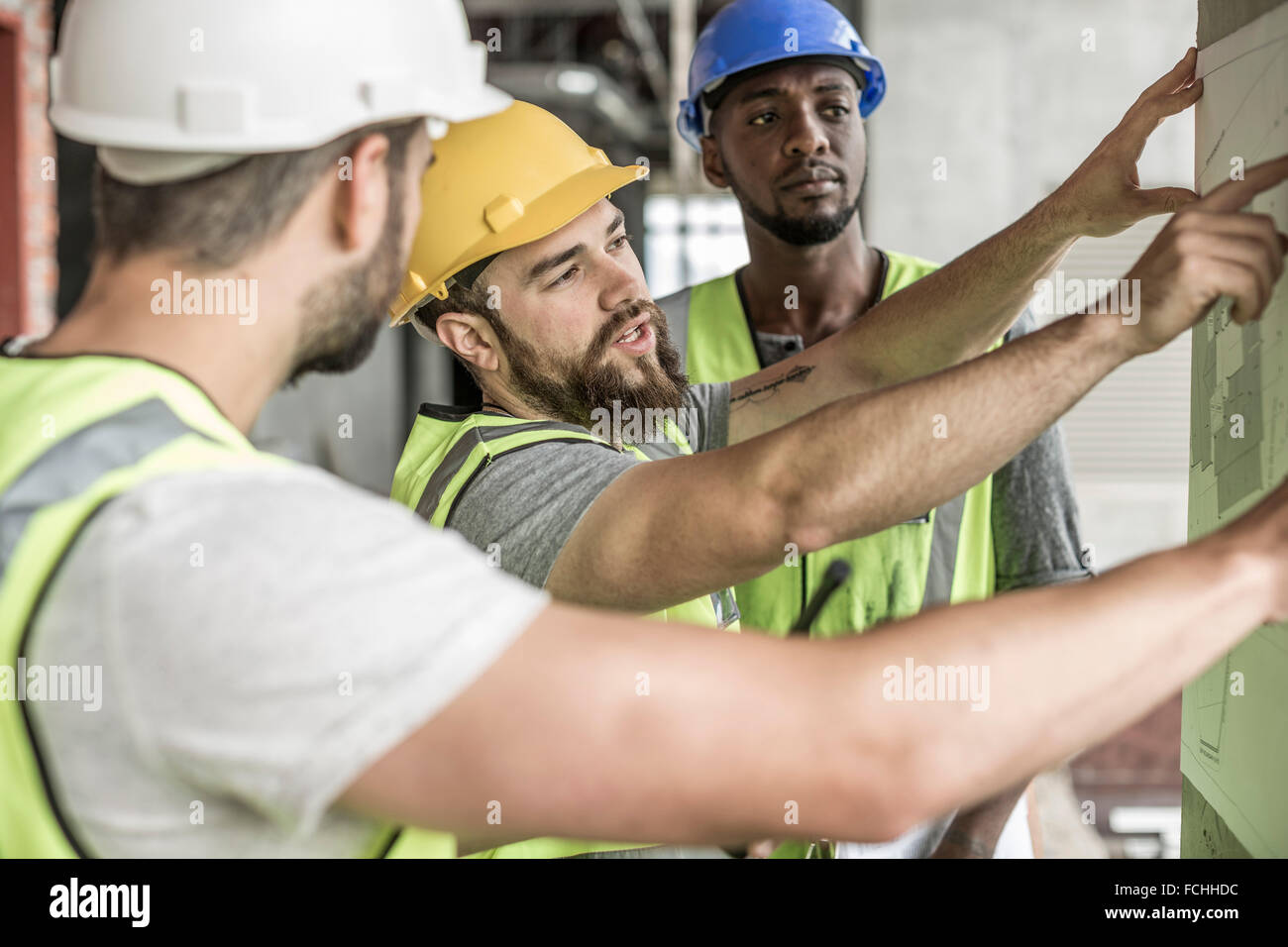 Construction workers discussing building plan in construction site ...