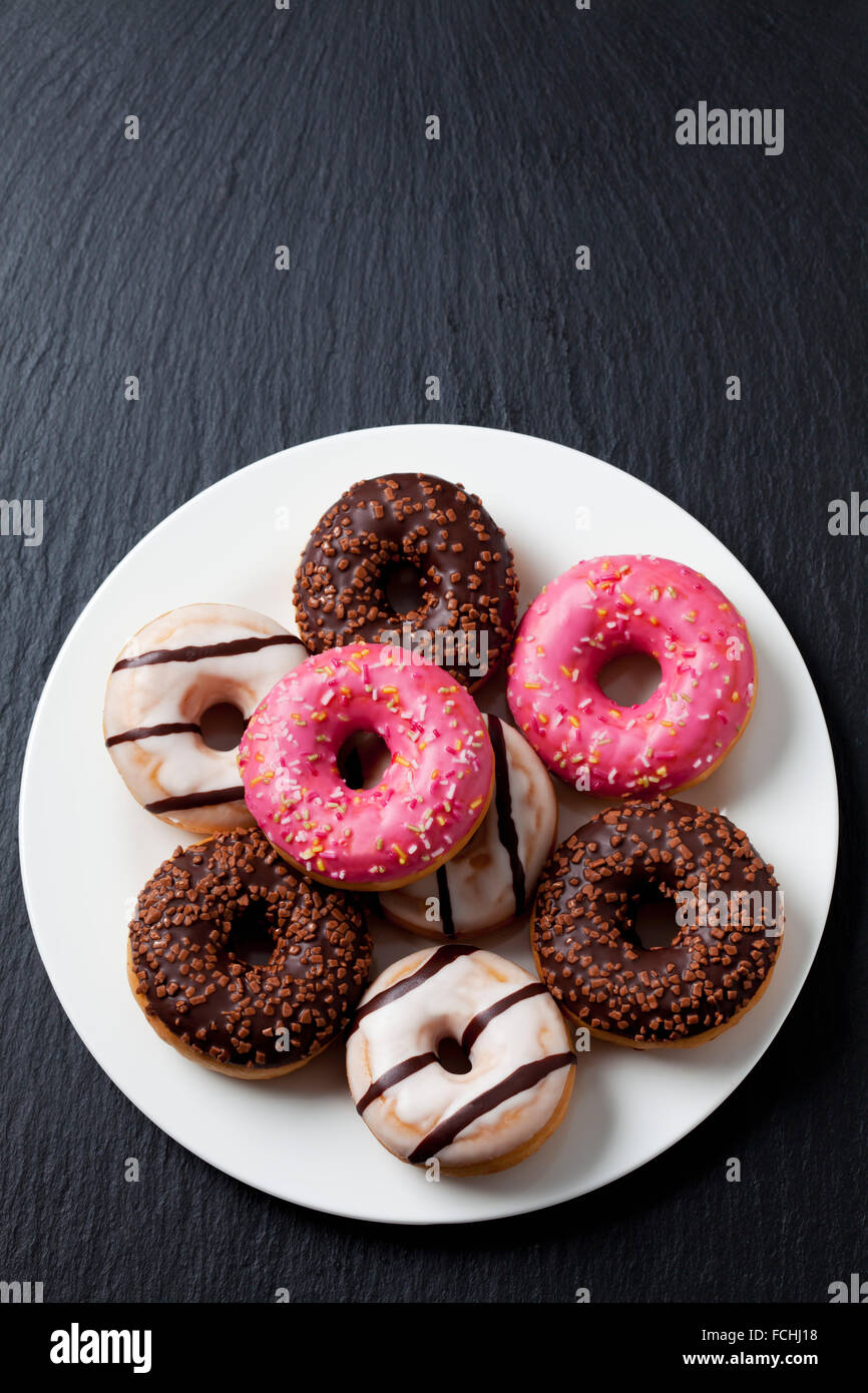 Plate of doughnuts different icings on slate Stock Photo - Alamy