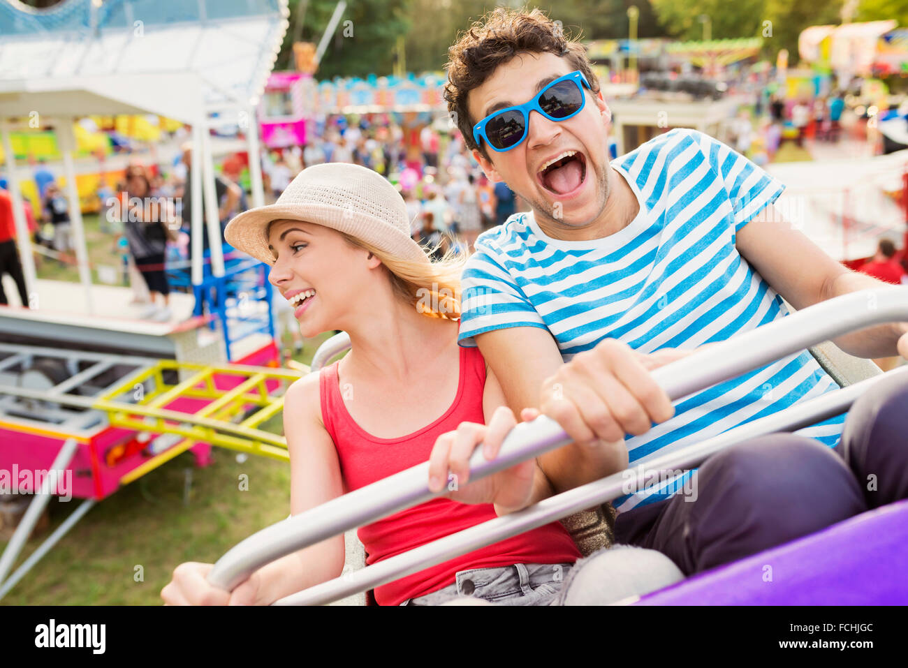 Happy couple at fun fair riding roller coaster Stock Photo - Alamy