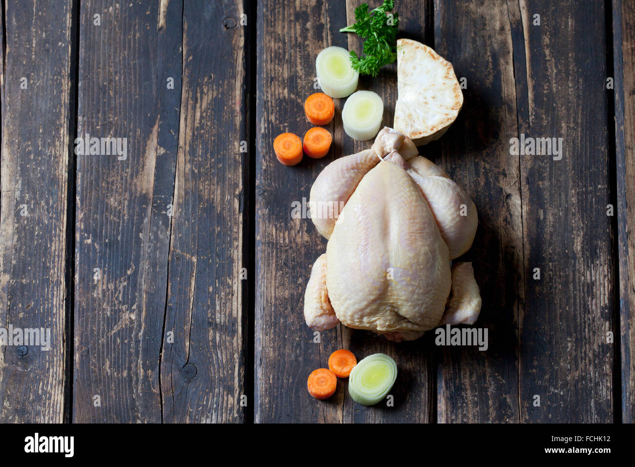 Raw corn-fed chicken and greens on dark wood Stock Photo - Alamy