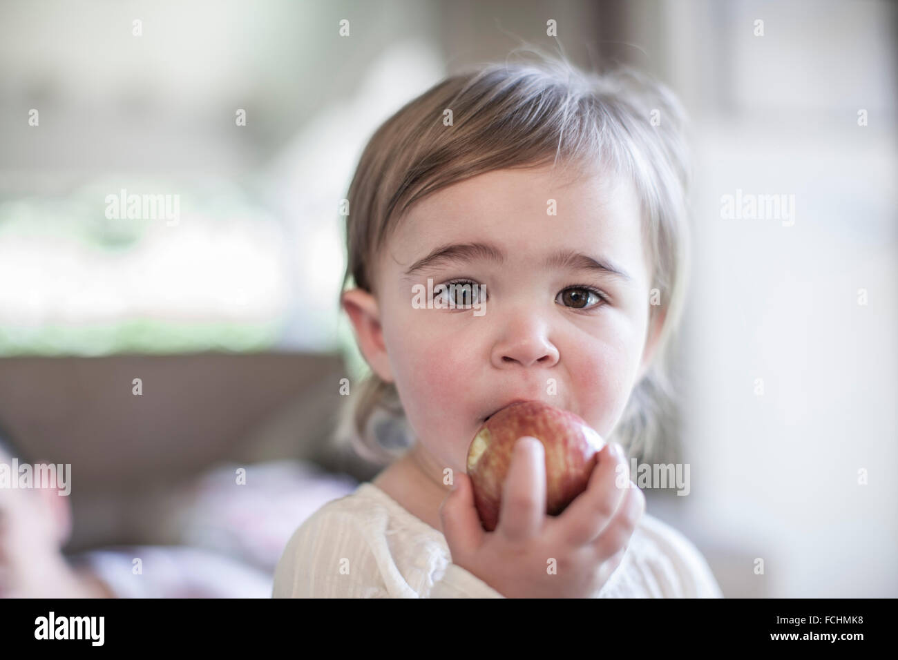 Baby girl eating an apple Stock Photo - Alamy