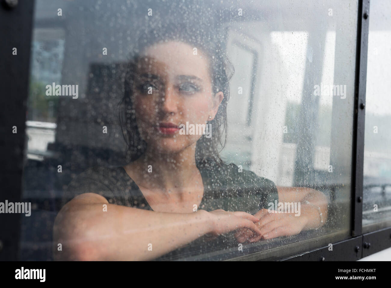 Portrait of young woman looking through window of an excursion boat on ...
