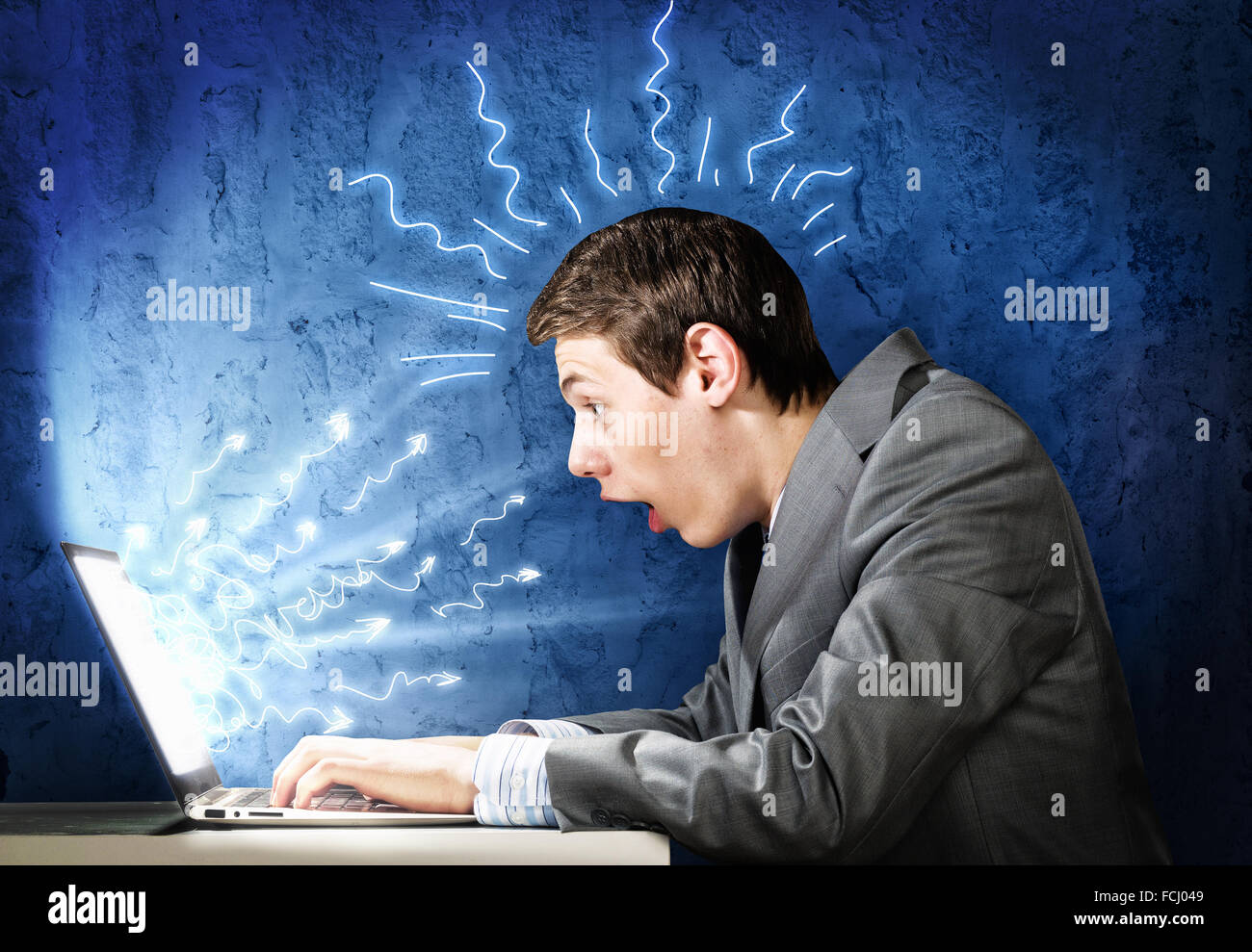 Young businessman looking shocked into laptop monitor hi-res stock ...