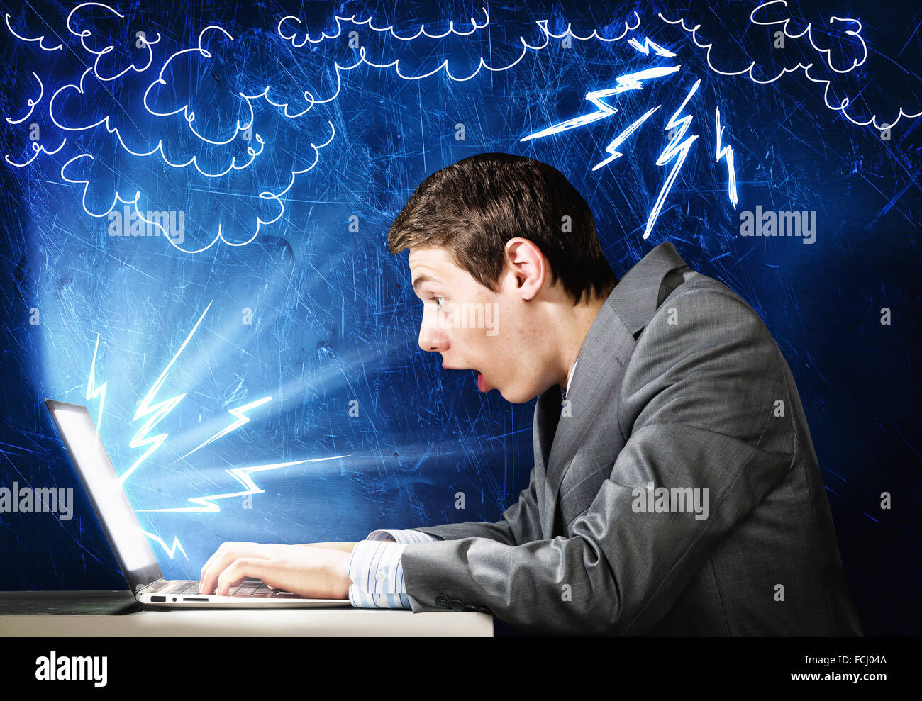Young businessman looking shocked into laptop monitor hi-res stock ...