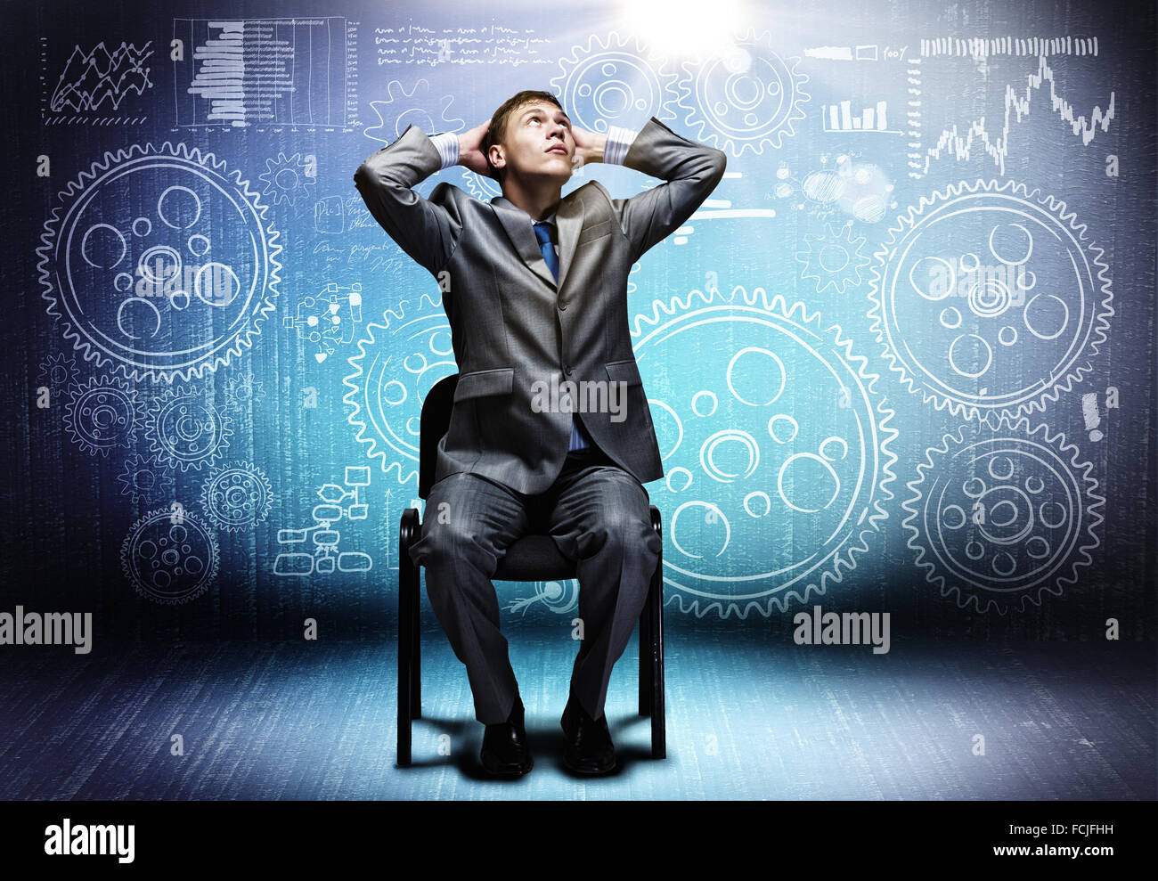 Young businessman sitting on chair and looking above Stock Photo - Alamy