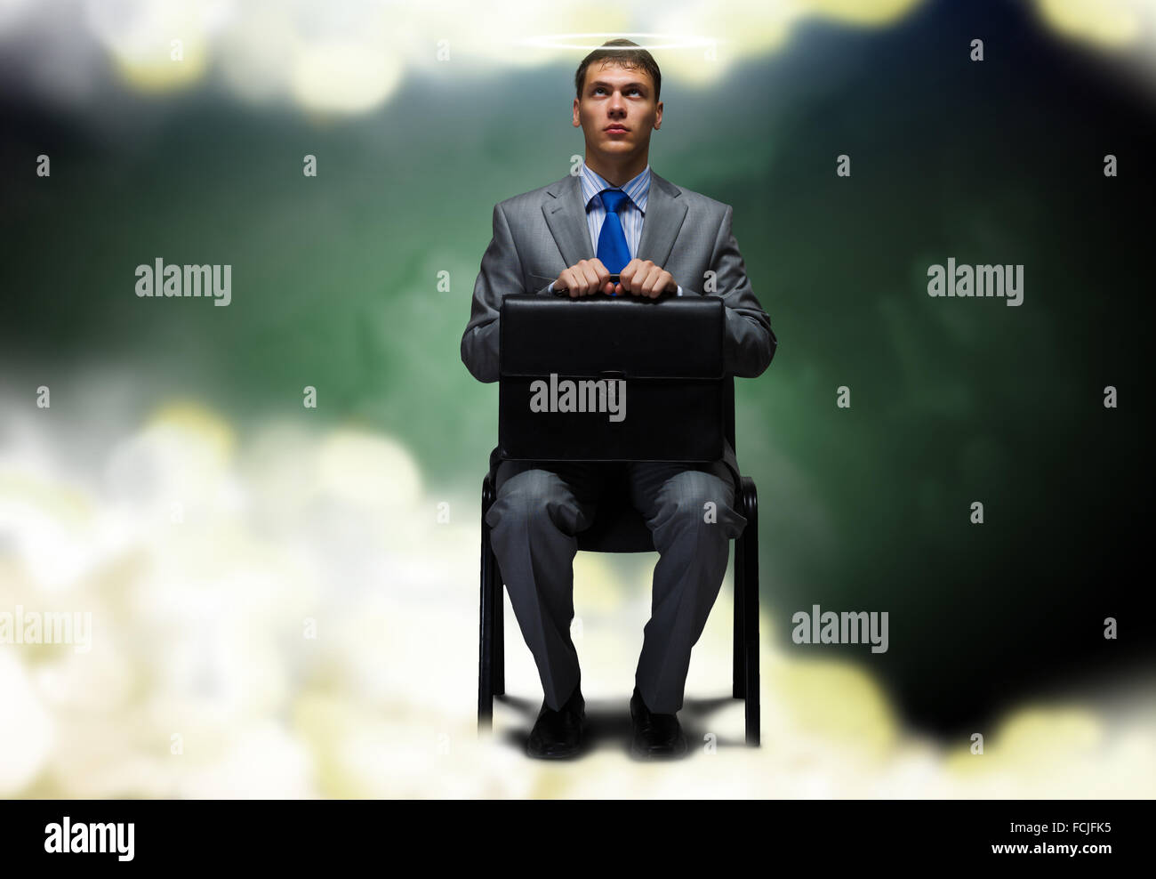 Young businessman with halo above head sitting on chair Stock Photo - Alamy