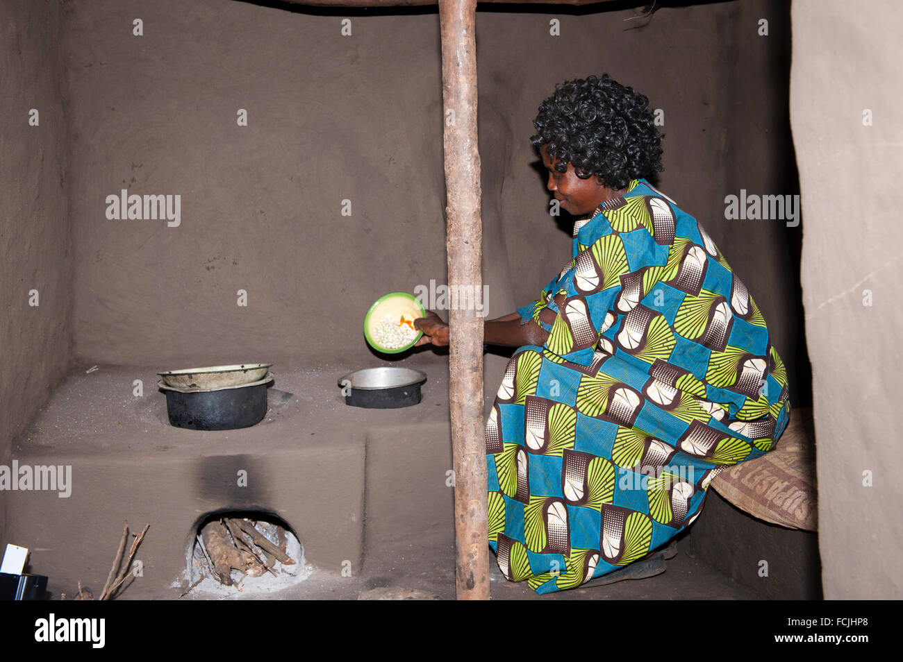Ugandan lady cooking on an energy efficent stove, which reduces carbon ...