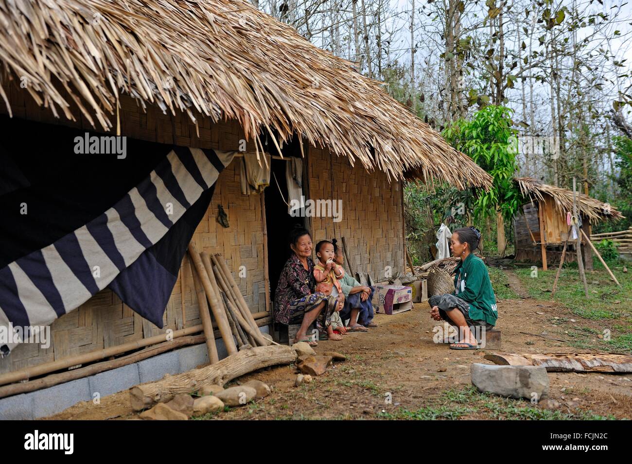 Hmong family sitting on the doorstep of their house in the mountain ...