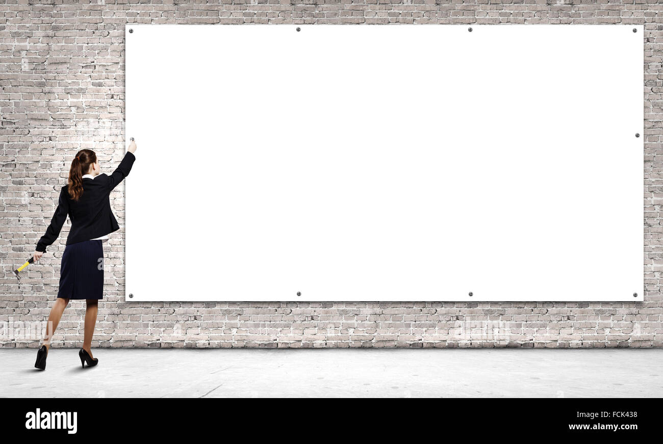 Rear view of businesswoman fixing white blank banner on wall Stock ...