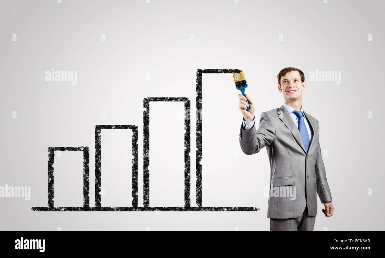 Young businessman painting graphs and diagrams with brush Stock Photo ...