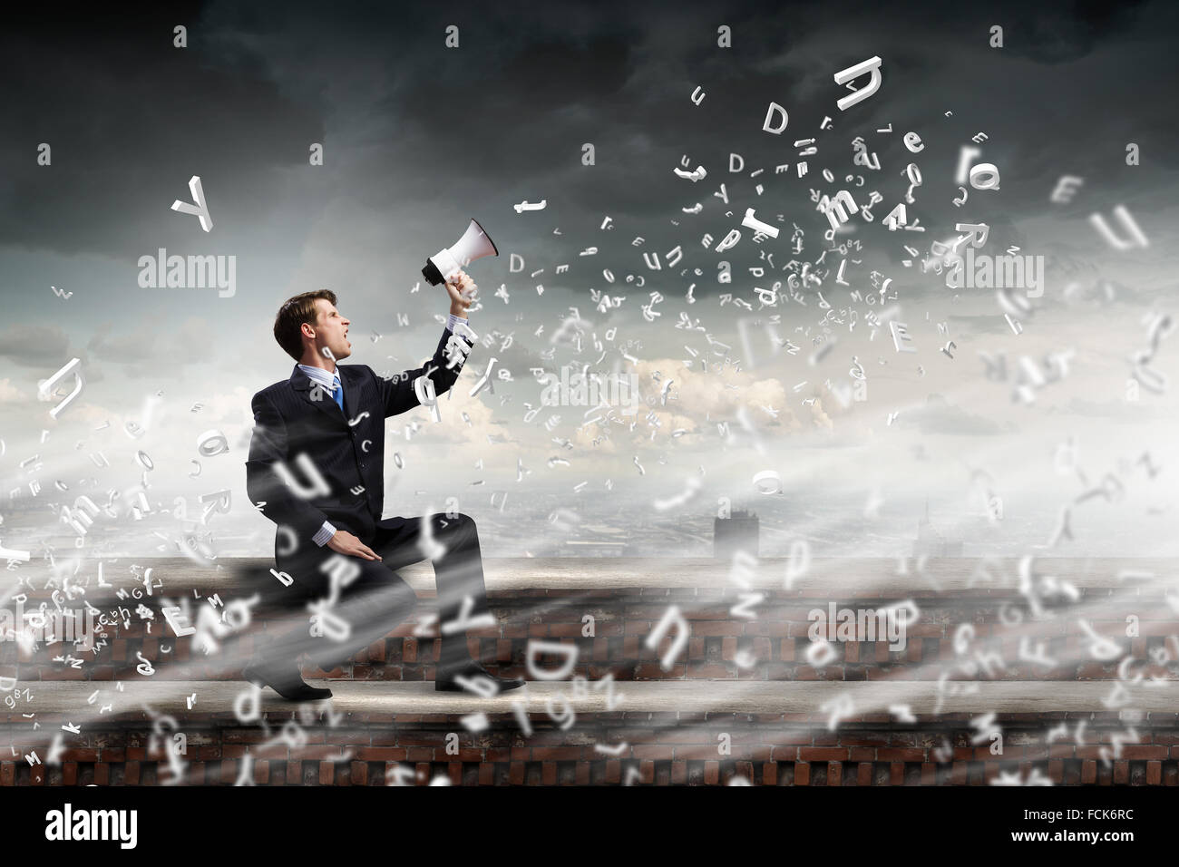 Young businessman on top of building screaming in megaphone Stock Photo ...