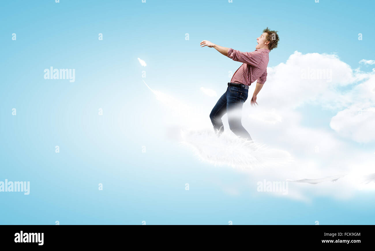 Young man walking on cloud high in sky Stock Photo - Alamy