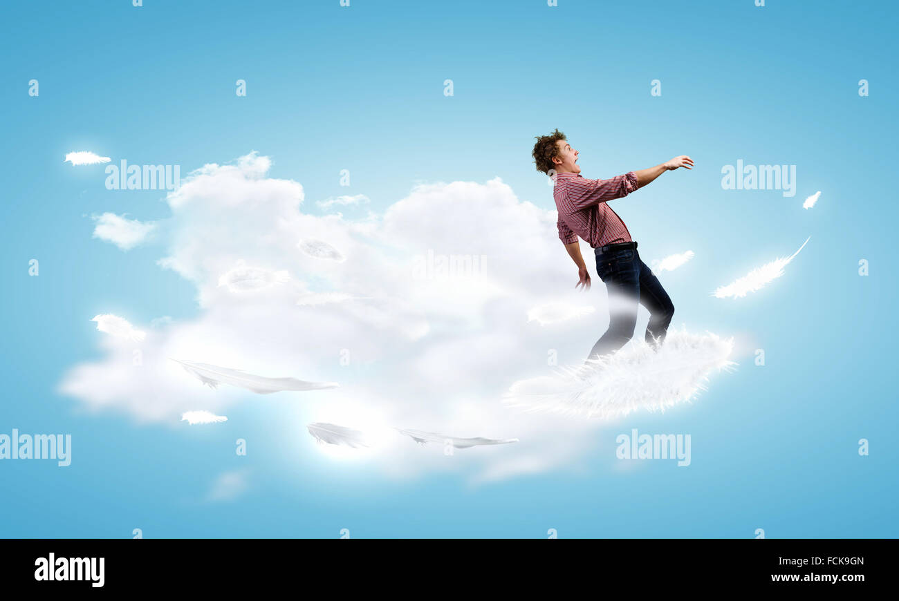 Young man walking on cloud high in sky Stock Photo - Alamy