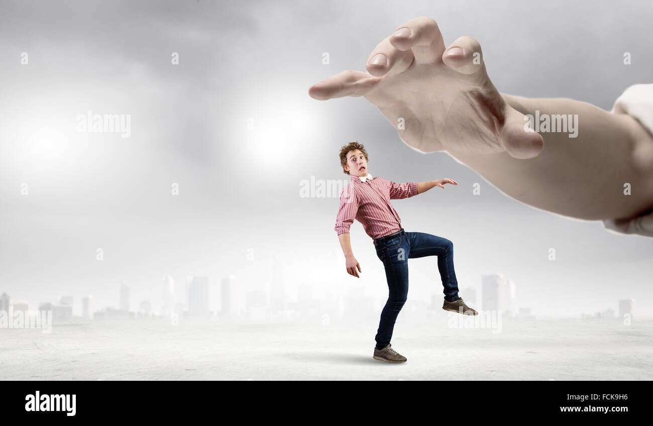 Young man in casual running away from big hand Stock Photo - Alamy