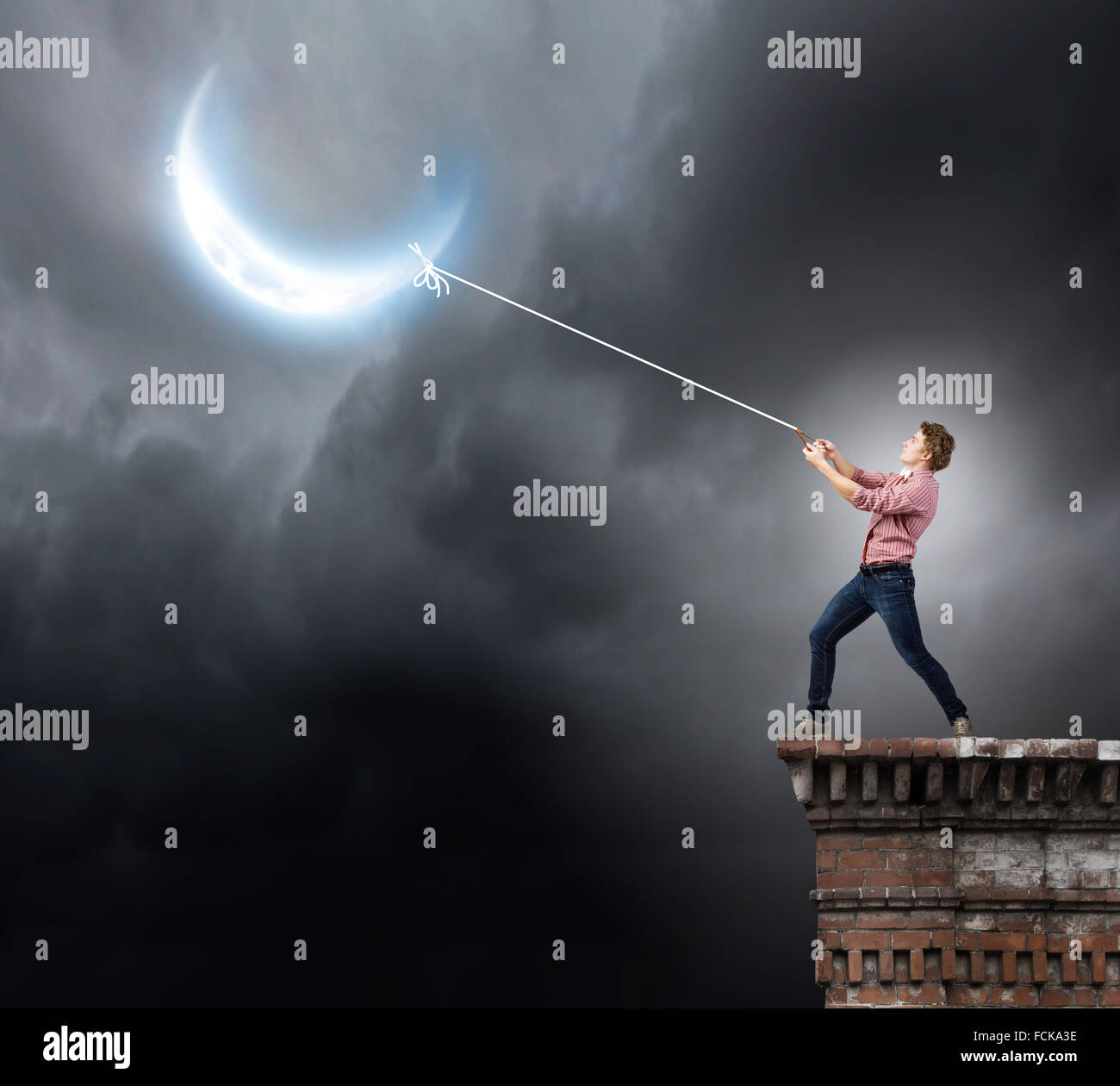 Young man in casual catching moon with rope Stock Photo - Alamy