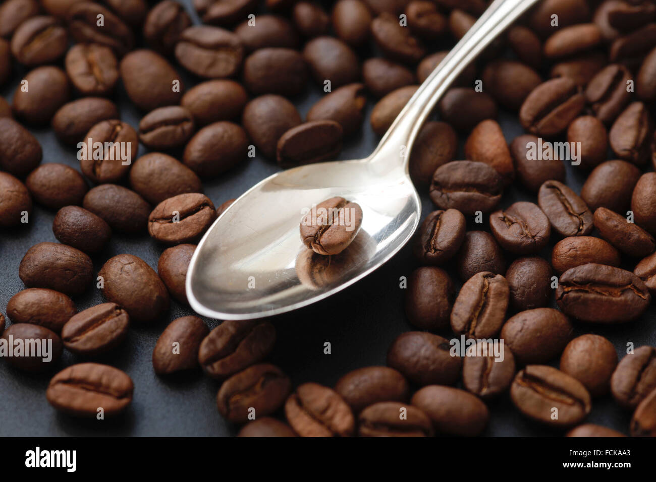 Silver spoon and roasted coffee beans Stock Photo - Alamy