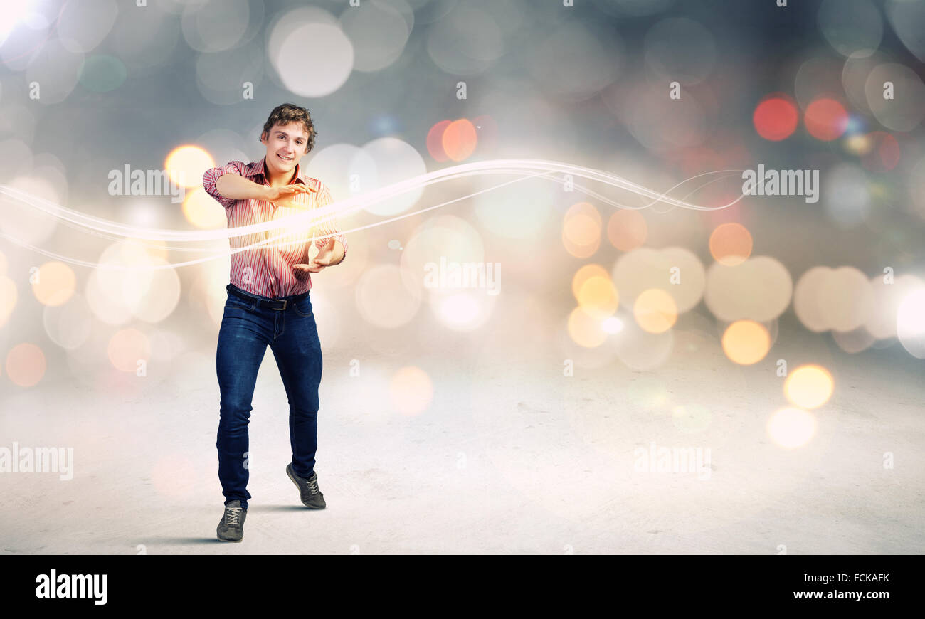 Young man in casual throwing magic light Stock Photo - Alamy