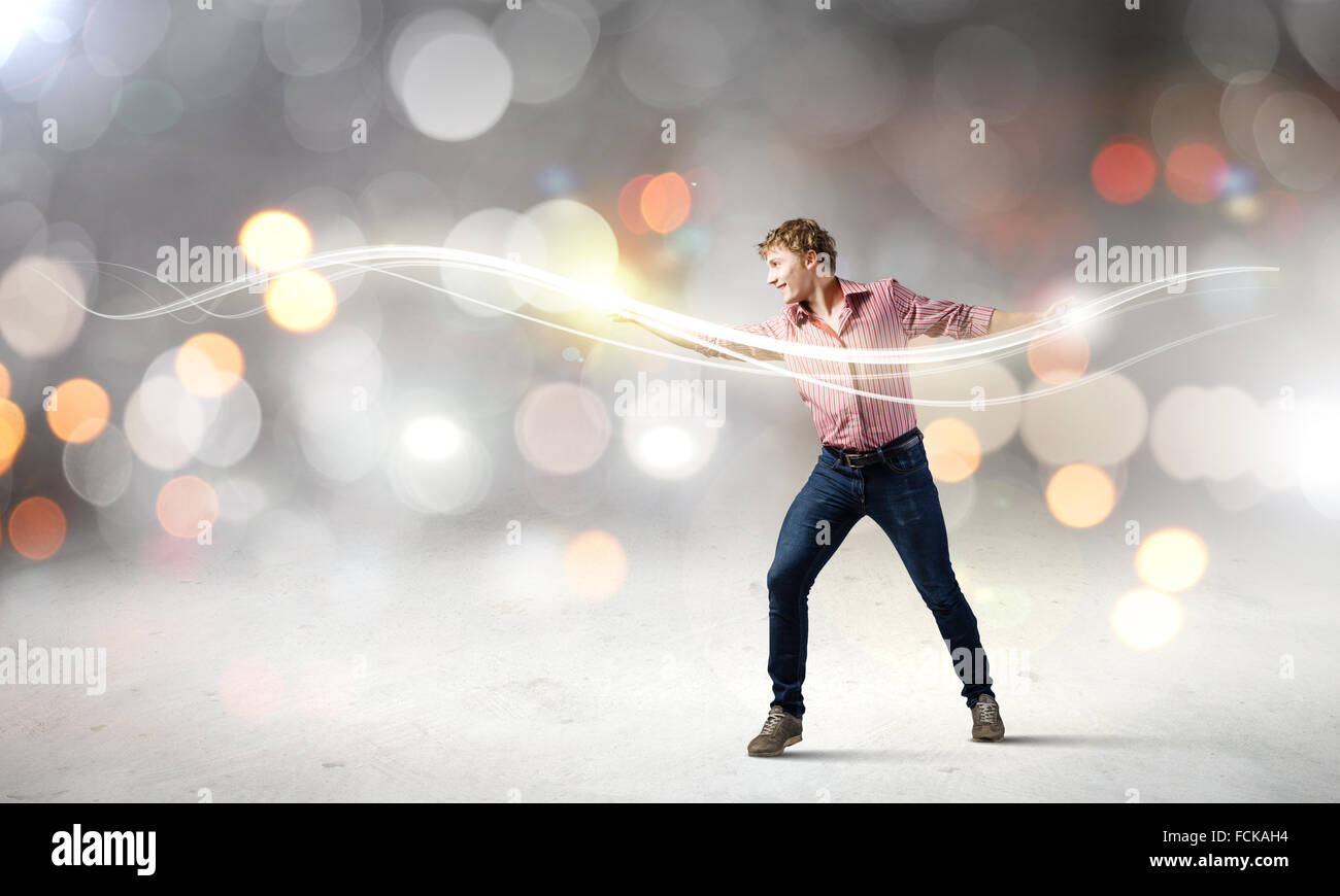 Young man in casual throwing magic light Stock Photo - Alamy
