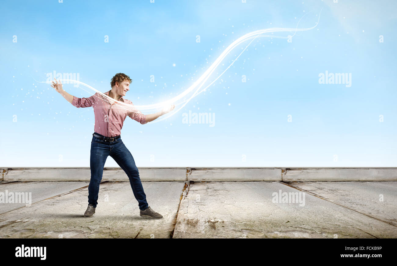 Young man in casual throwing magic light Stock Photo - Alamy