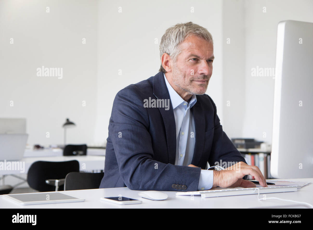 Businessman in office at desk using computer Stock Photo - Alamy