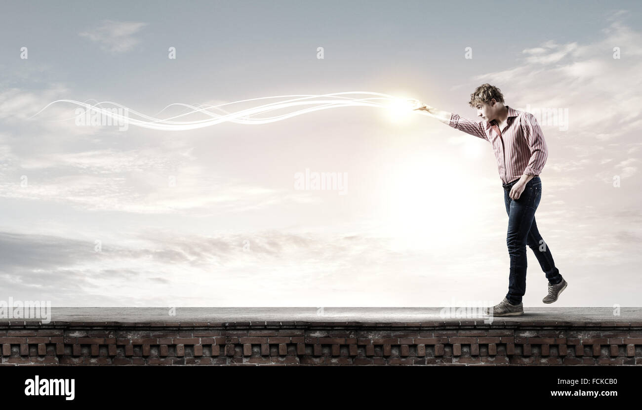 Young man in casual throwing magic light Stock Photo - Alamy