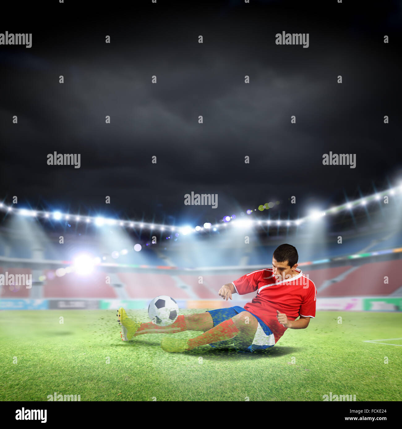 Football player at stadium sliding to kick the ball Stock Photo - Alamy