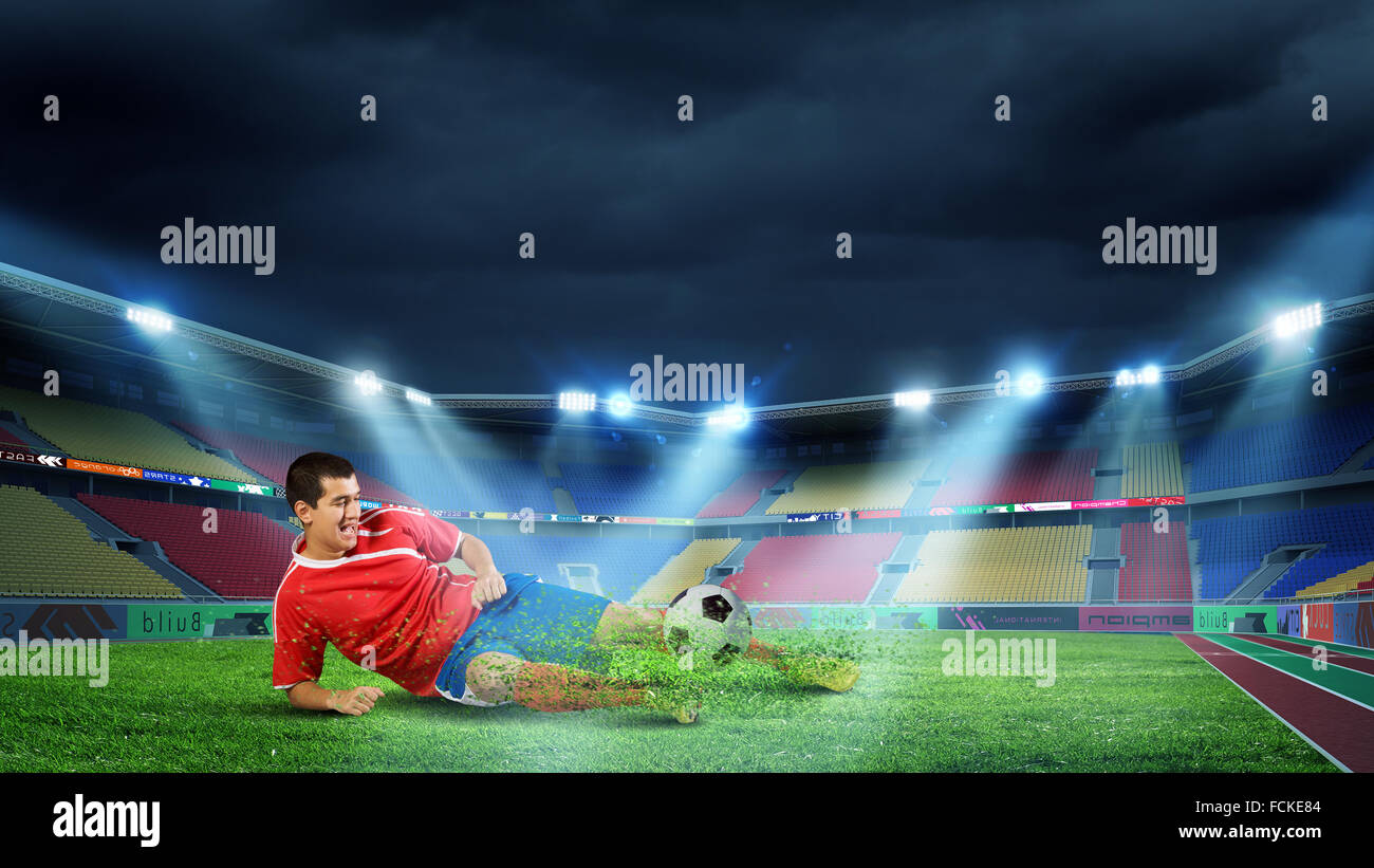Football player at stadium sliding to kick the ball Stock Photo - Alamy