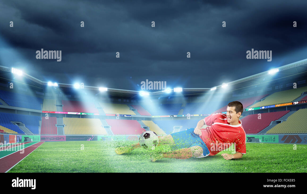 Football player at stadium sliding to kick the ball Stock Photo - Alamy