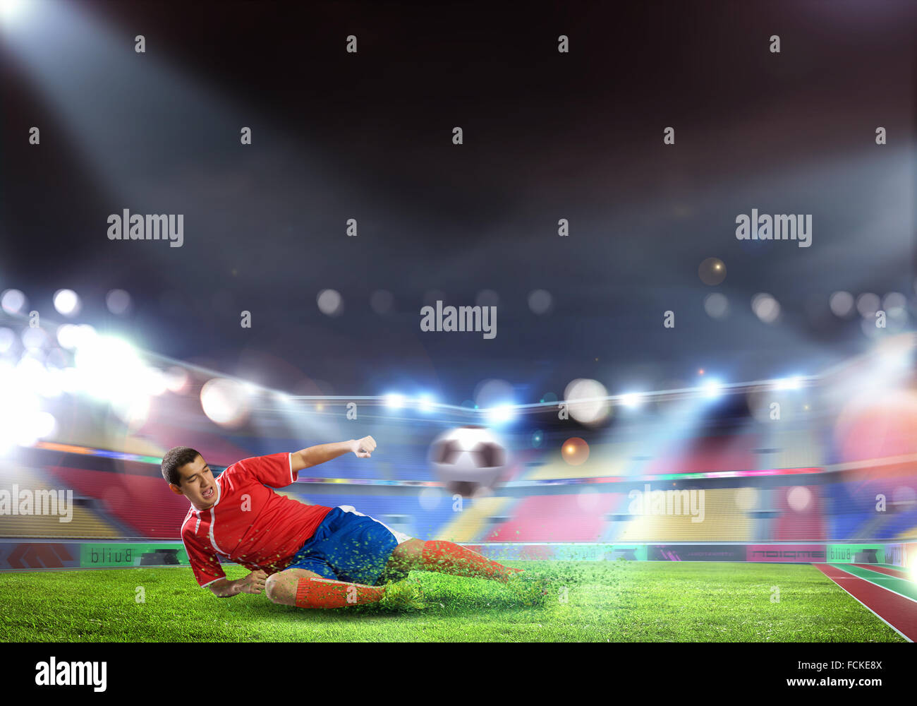 Football player at stadium sliding to kick the ball Stock Photo - Alamy