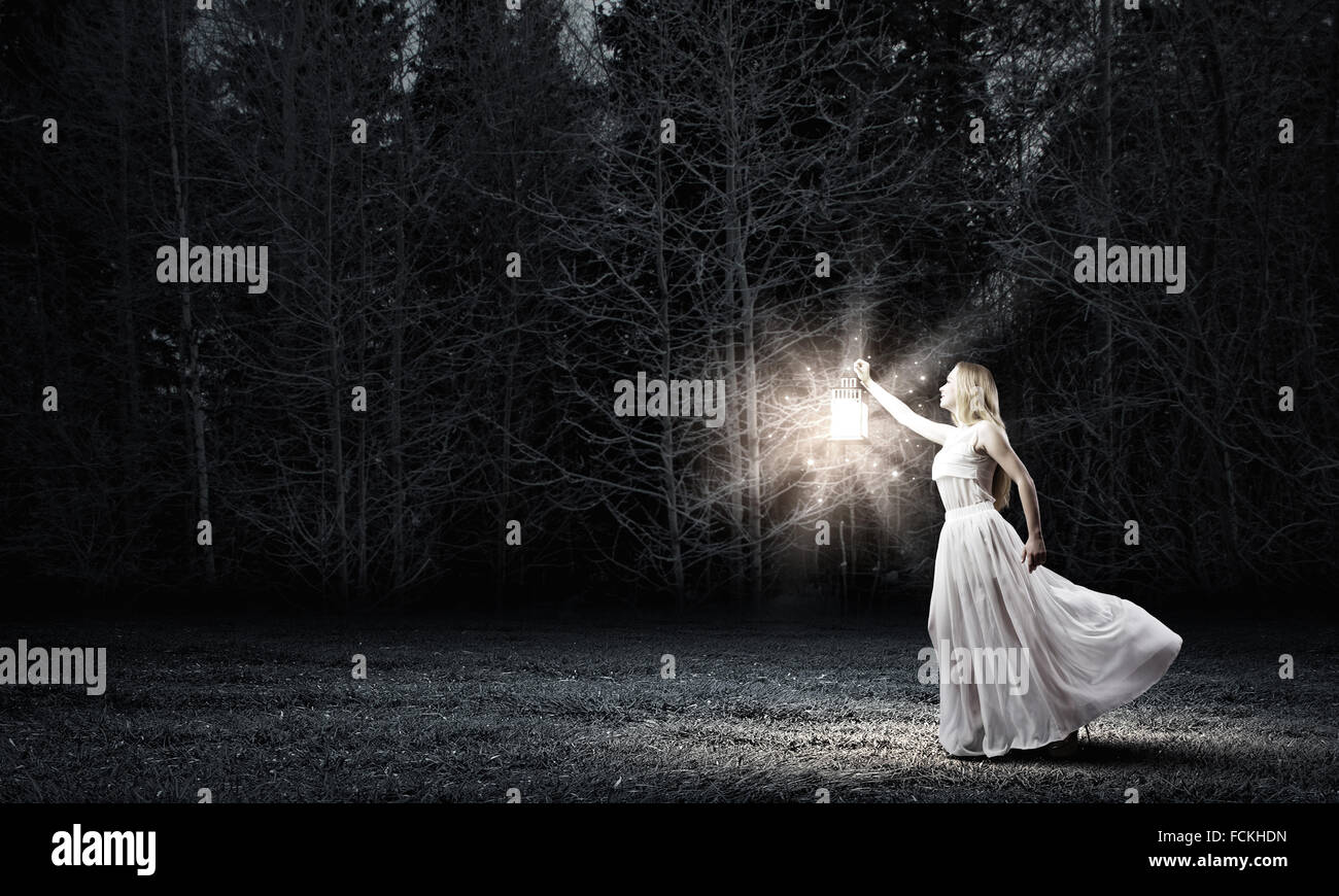 Young woman with lantern walking in dark forest Stock Photo - Alamy