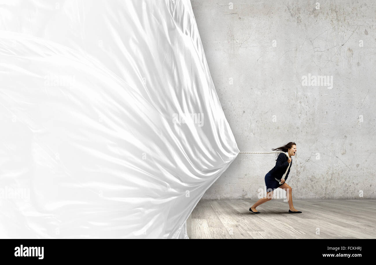 Young determined businesswoman pulling white blank banner with rope ...