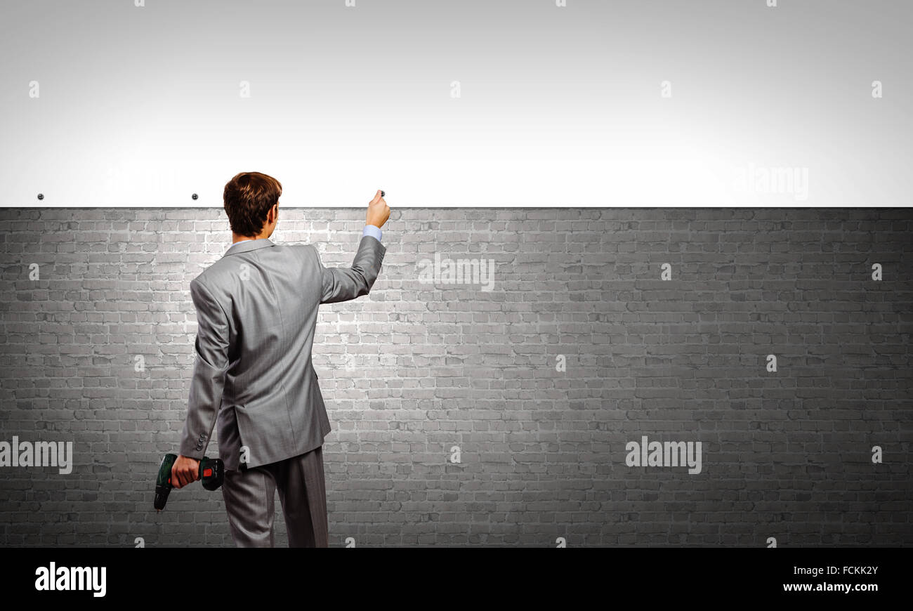 Rear view of businessman fixing white blank banner with drill Stock ...
